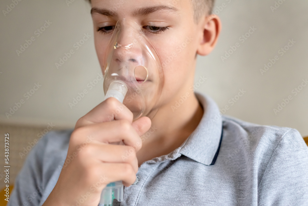 Sick teen boy with an inhaler. Unhealthy child doing inhalation at home ...