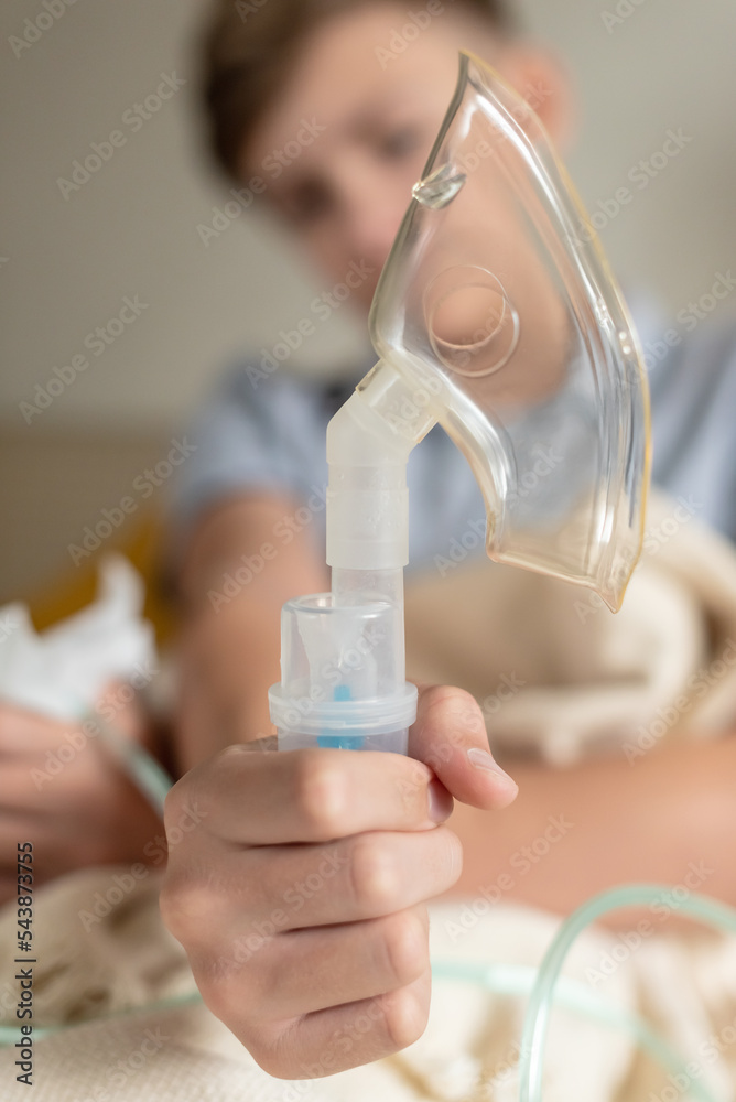Sick teen boy with an inhaler. Unhealthy child doing inhalation at home ...
