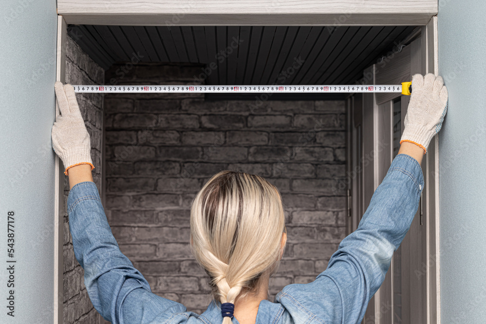 Woman measuring a doorway with a tape measure. woman using a tape ...