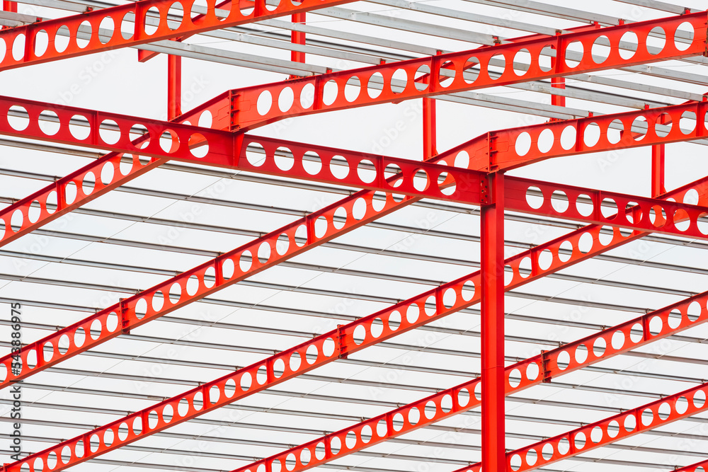 Red castellated beam metal roof structure of large industrial building ...