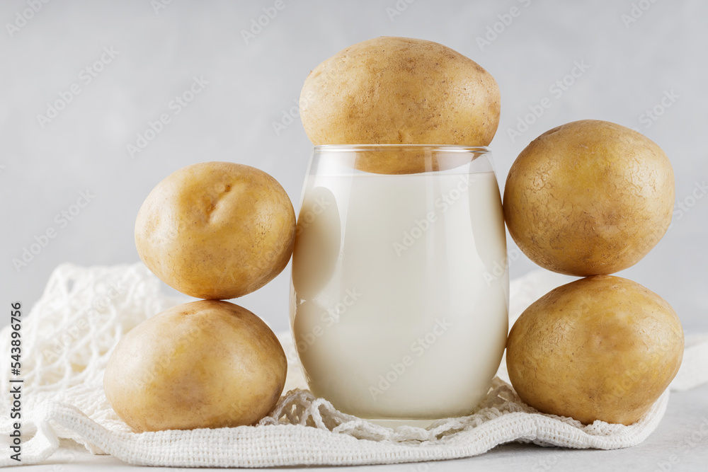 Potato milk and potatoes on a mesh bag. Plant based milk replacer and ...