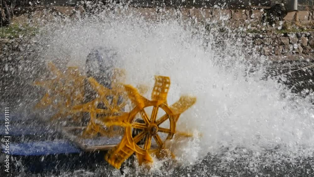 The paddle aerator rotates in the fish farm pond, oxygenating the water ...