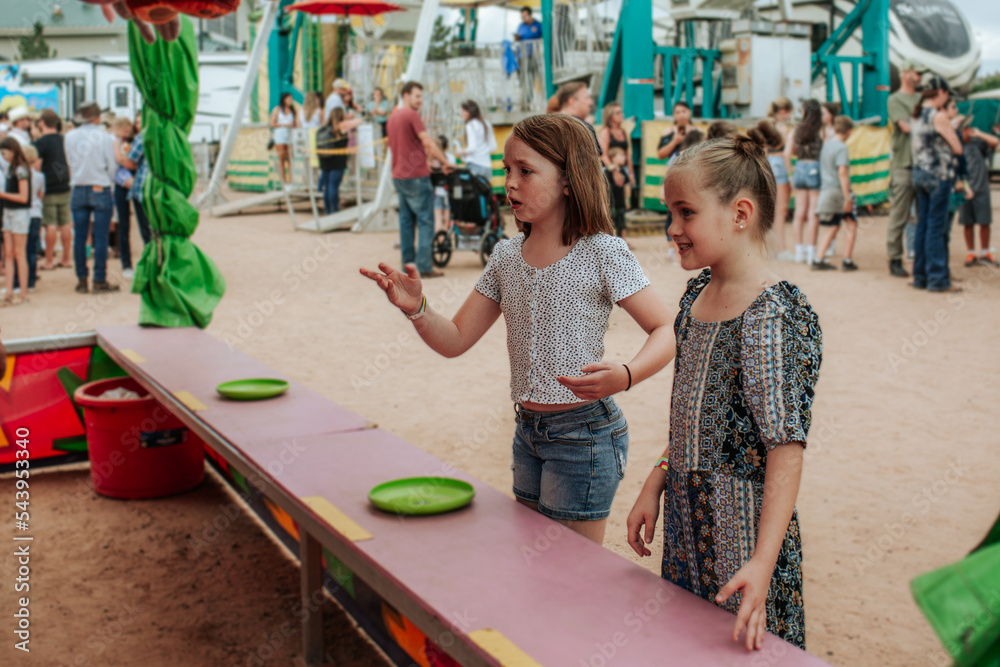 Two young girls playing carnival games at county fair Stock Photo ...