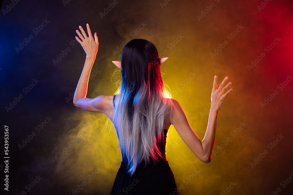 Rear back view of Elf queen in fantasy rope long dress cast spell ...