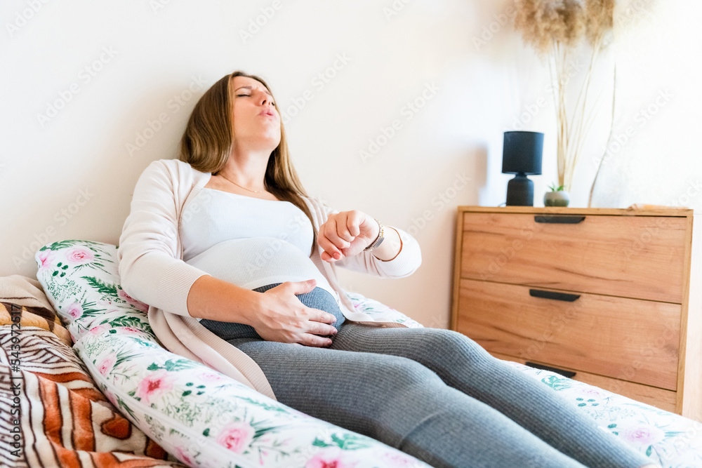 Pregnant contractions time. Pregnancy woman watching clock, holding ...