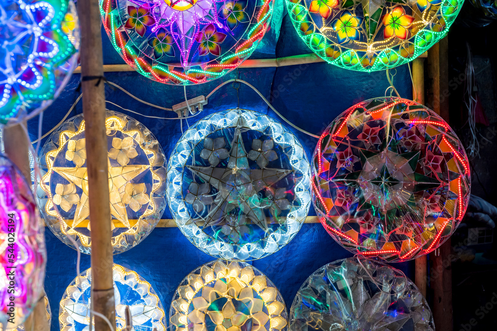 A stall by the street selling various lighted Christmas Parols. Parols ...