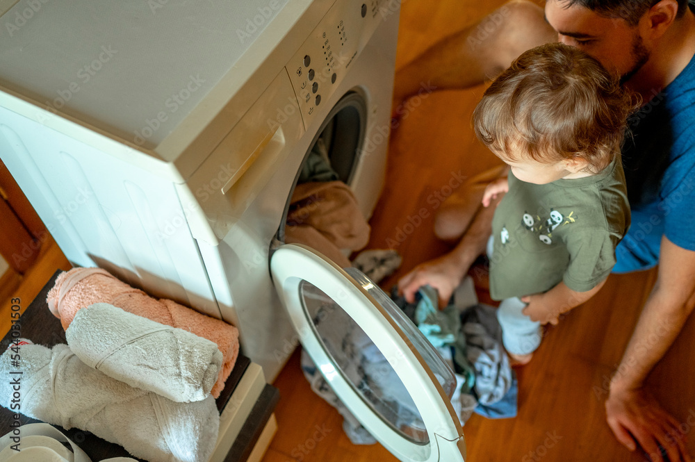 Son with father loading clothes in washing machine Stock Photo | Adobe ...