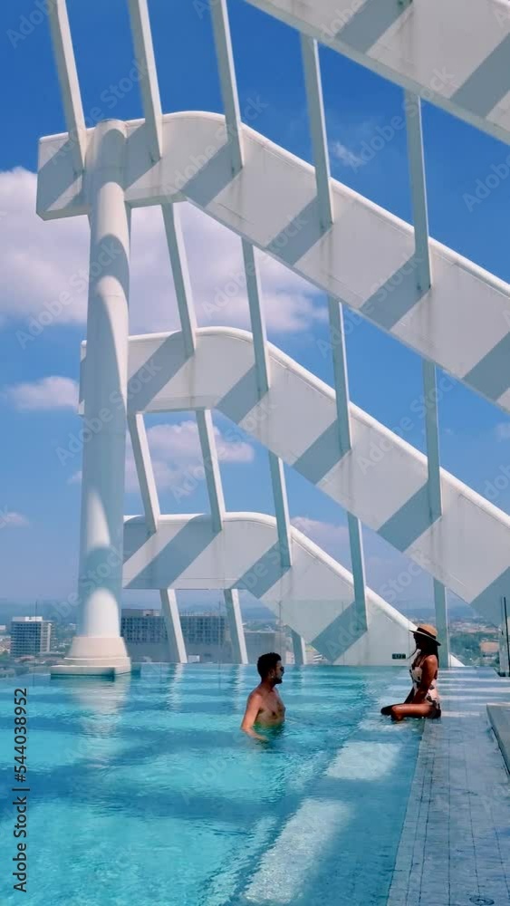 couple of men and women relaxing at a rooftop pool of a luxury hotel ...