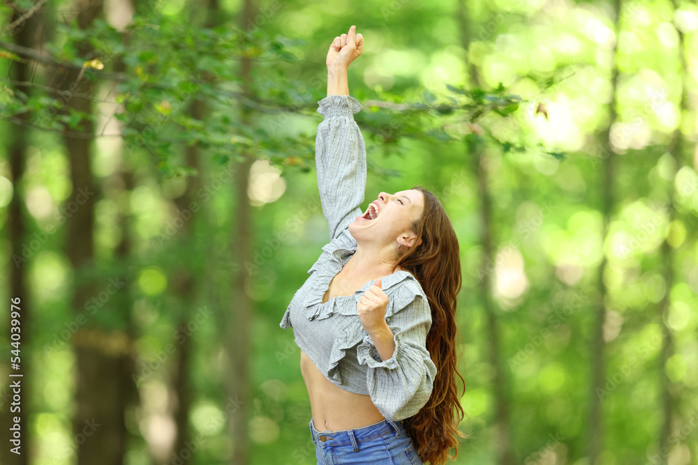 Euphoric woman celebrating in a forest raising arm Stock-Foto | Adobe Stock
