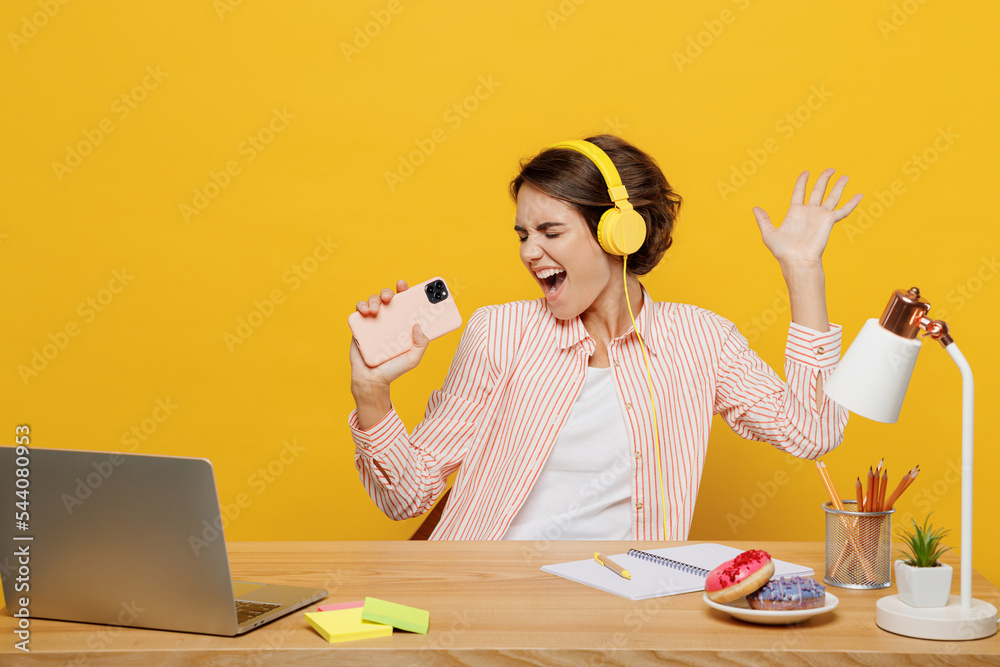 Young employee business woman wear casual shirt headphones listen music ...