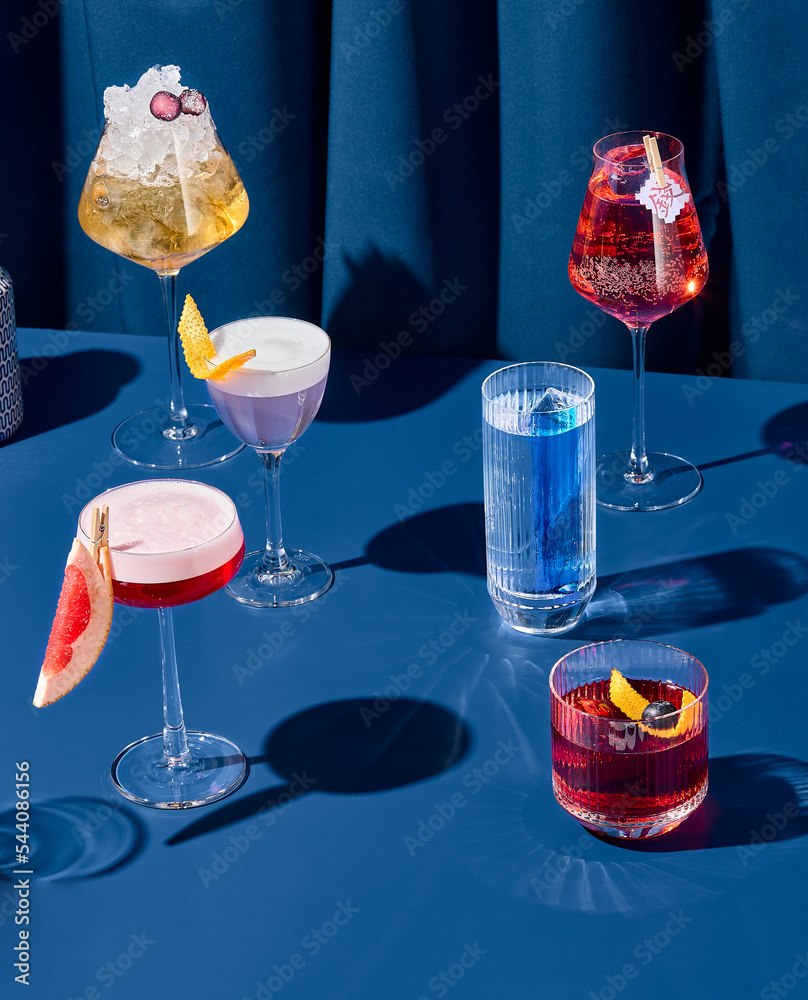 Composition with alcohol cocktails on coloured background with harsh ...