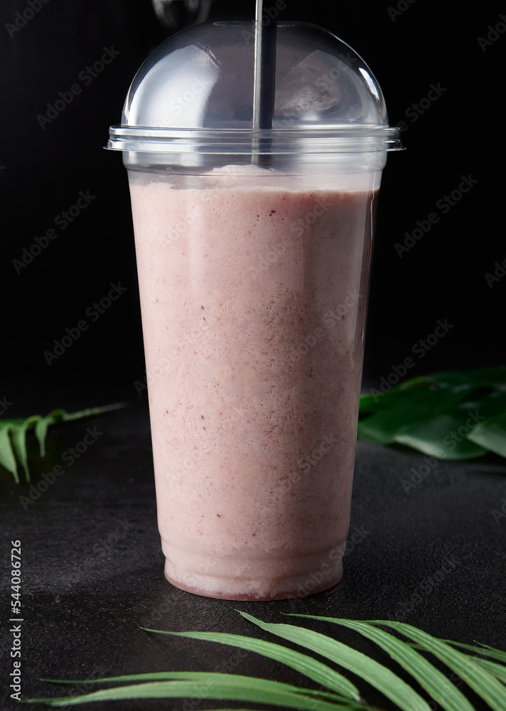 Strawberry shake in take out glass on dark background with leaves. Mock ...