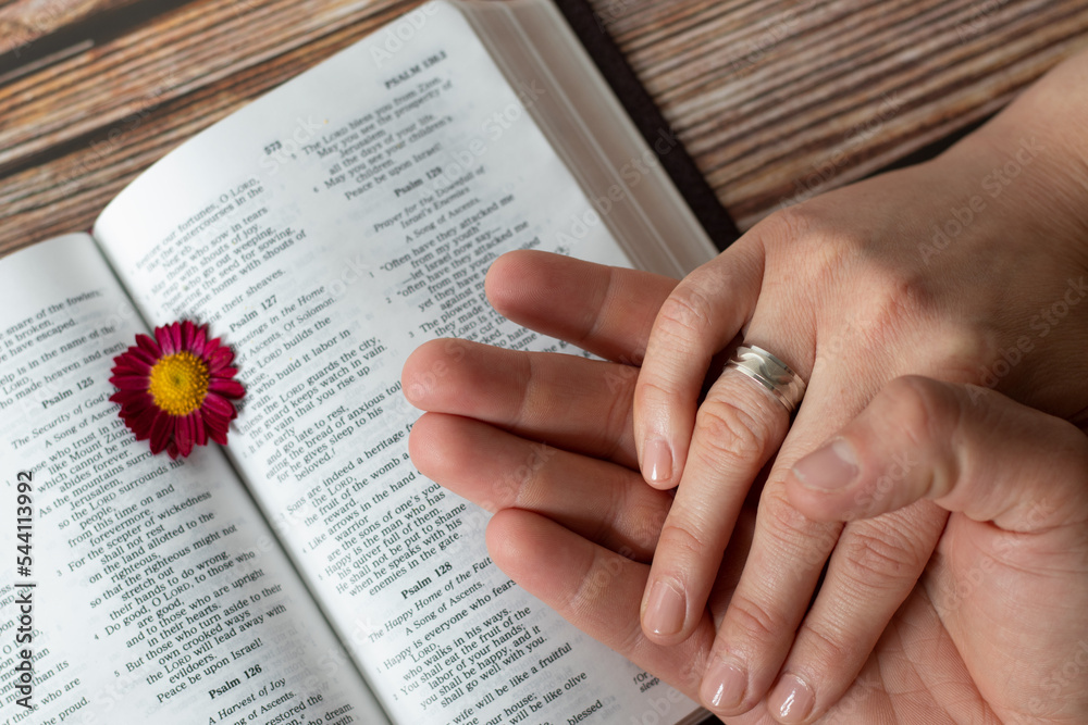 Christian couple hands with rings holding in prayer over open Holy ...