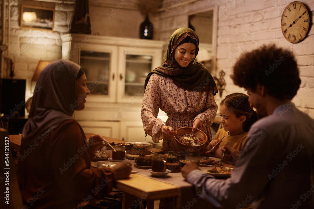 Young Muslim woman serving food to her family at dining table. Stock ...