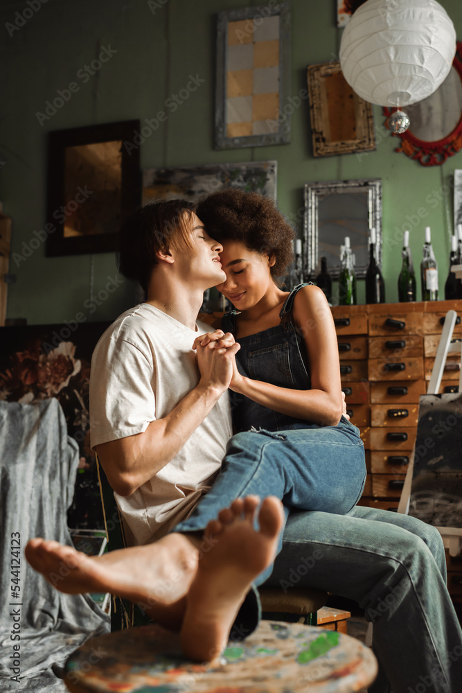 barefoot african american woman in denim overalls holding hands with ...
