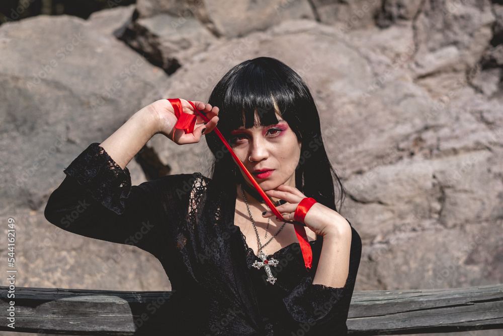 Young, sexy and vampiric hispanic goth girl with black dress seated and ...
