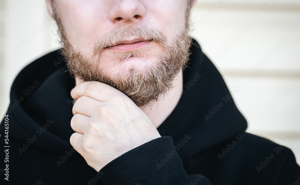 Close-up, a young man touches his beard with his hand. Stock Photo ...
