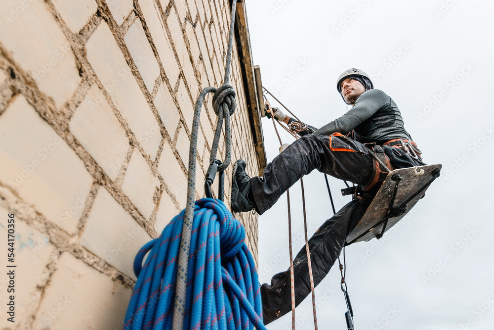 Male worker rope access industrial working at height tank oil wearing ...