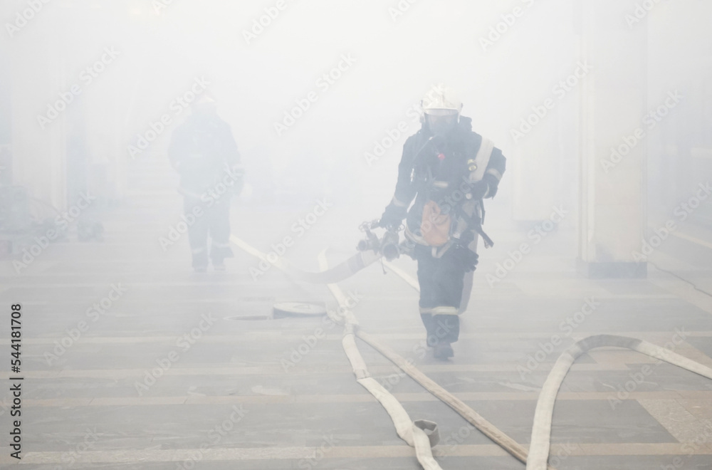 Rescuers firefighters go in the smoke, carry equipment. Stock Photo ...