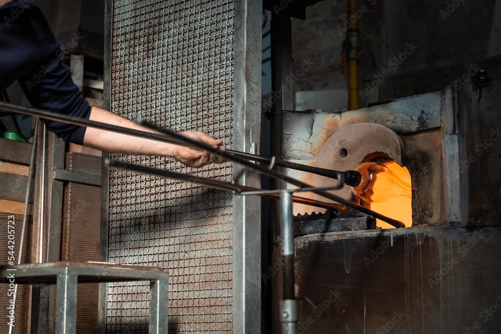 "Murano glass blowing factory. Workers put iron rod in furnace to make ...