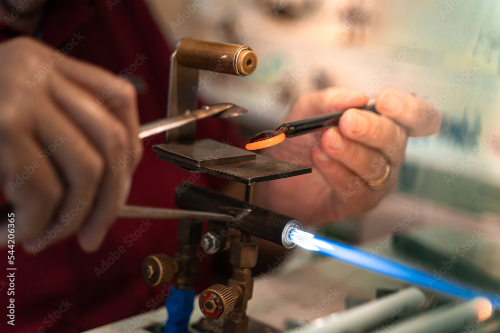 Murano glass blowing factory. Workers put iron rod in furnace to make ...