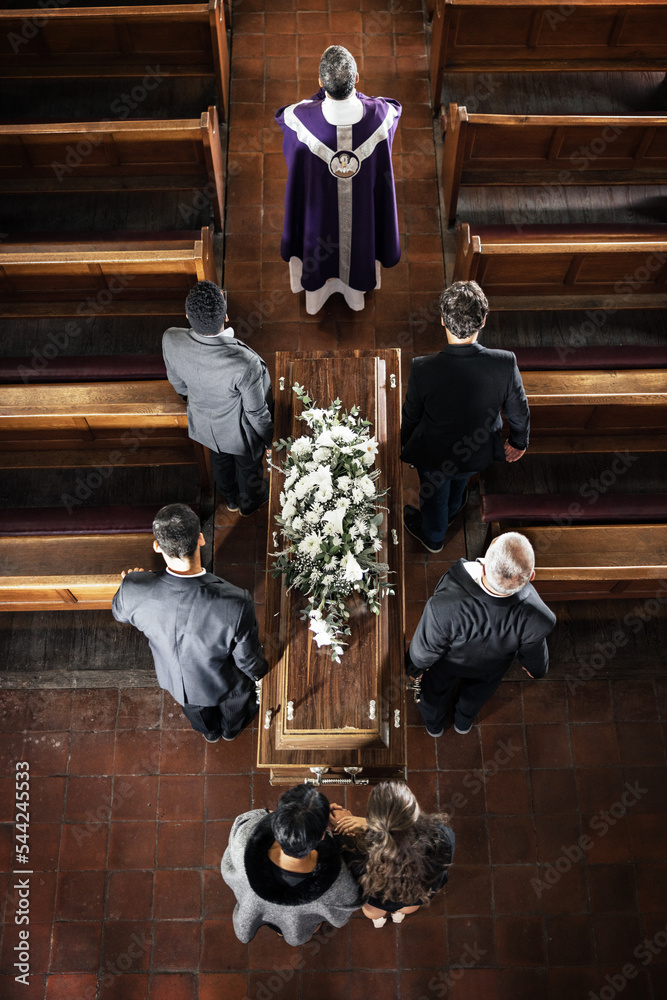 Funeral, church and sad people carrying coffin with a priest ...