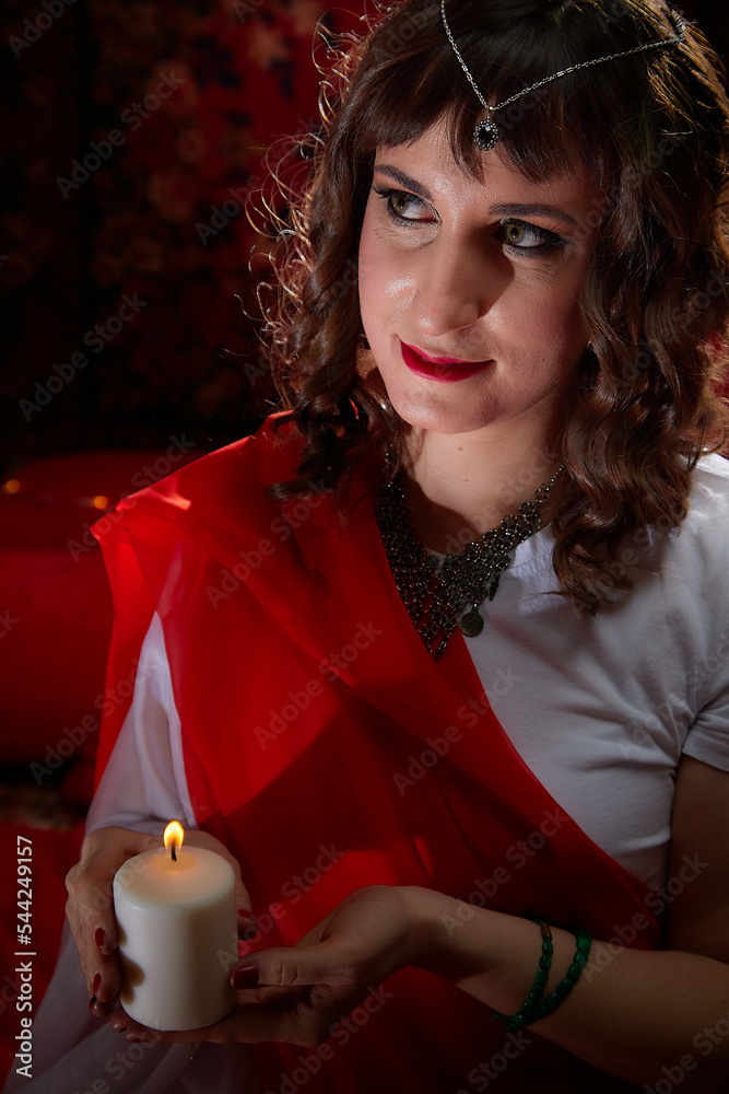 Beautiful arabian girl with candles in red room full of rich fabrics ...