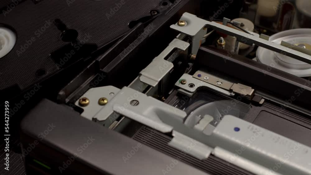 Close up VHS video cassette insert in recorder in VCR player. Tape play ...