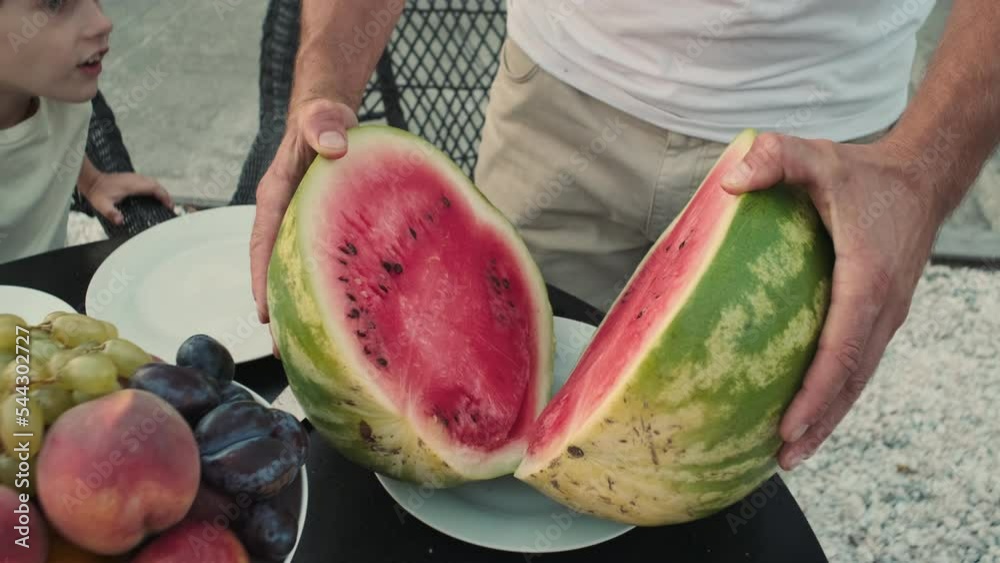 A man opens a cut watermelon on the table. Stock Video | Adobe Stock