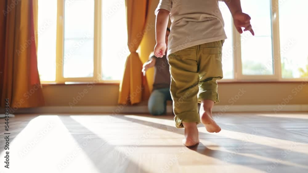 baby runs to mom at home. a child with bare legs runs across the floor ...