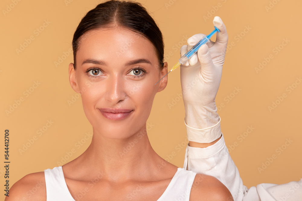 Happy young beautiful woman getting facial injection in cheekbones zone ...