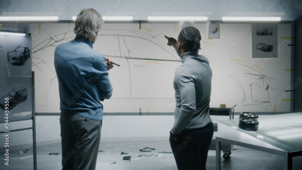 Two diverse automotive male designers standing near sketch on ...