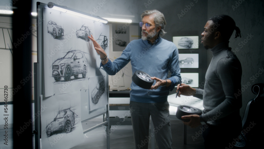 Two diverse automotive male designers holding small wheels, developing ...