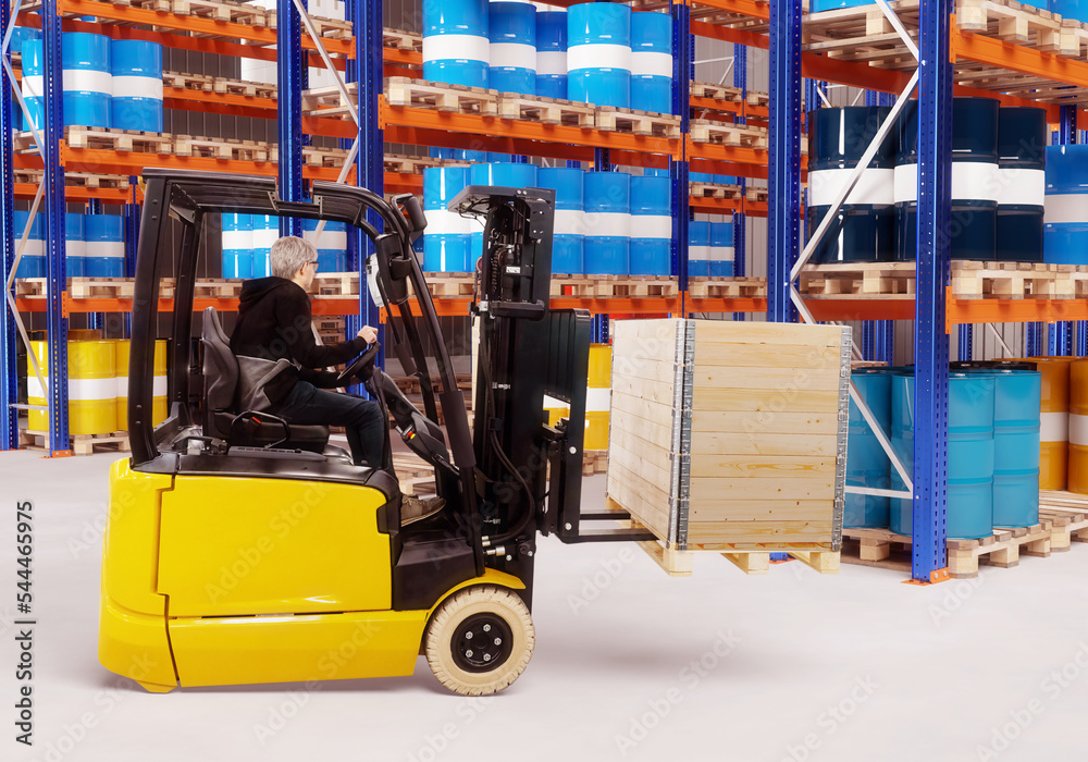 Forklift in logistics center. Man drives forklift with pallet. Large ...