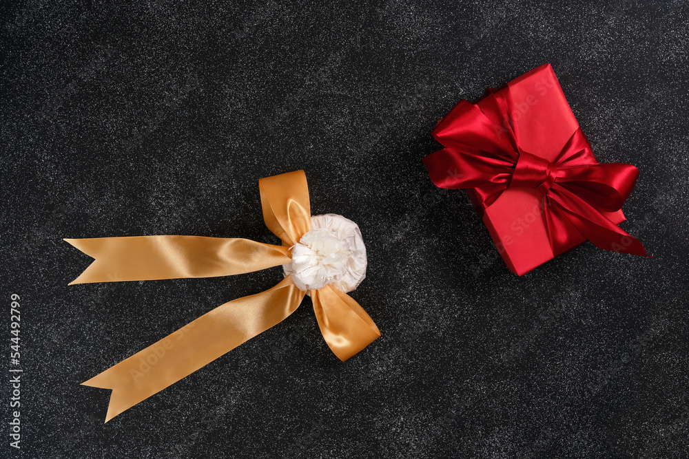 Two gifts wrapped in paper and tied with a ribbon in a bow on a black ...