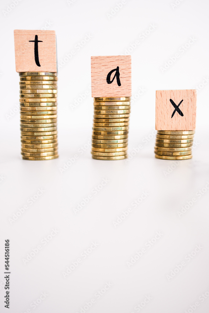 Tax text on top of decreasing stacks of coins, decreasing tax rates and ...
