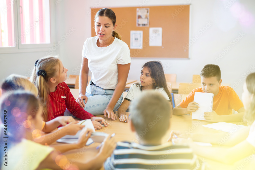 Schoolchildren and teacher brainstorming round table in school ...
