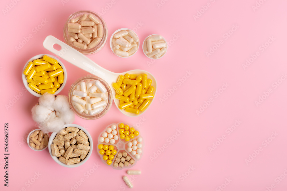 Organic food supplements in jars and small plates on pink background ...