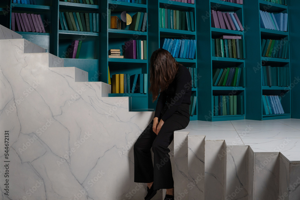 A sad student is sitting on a strange staircase against the background ...