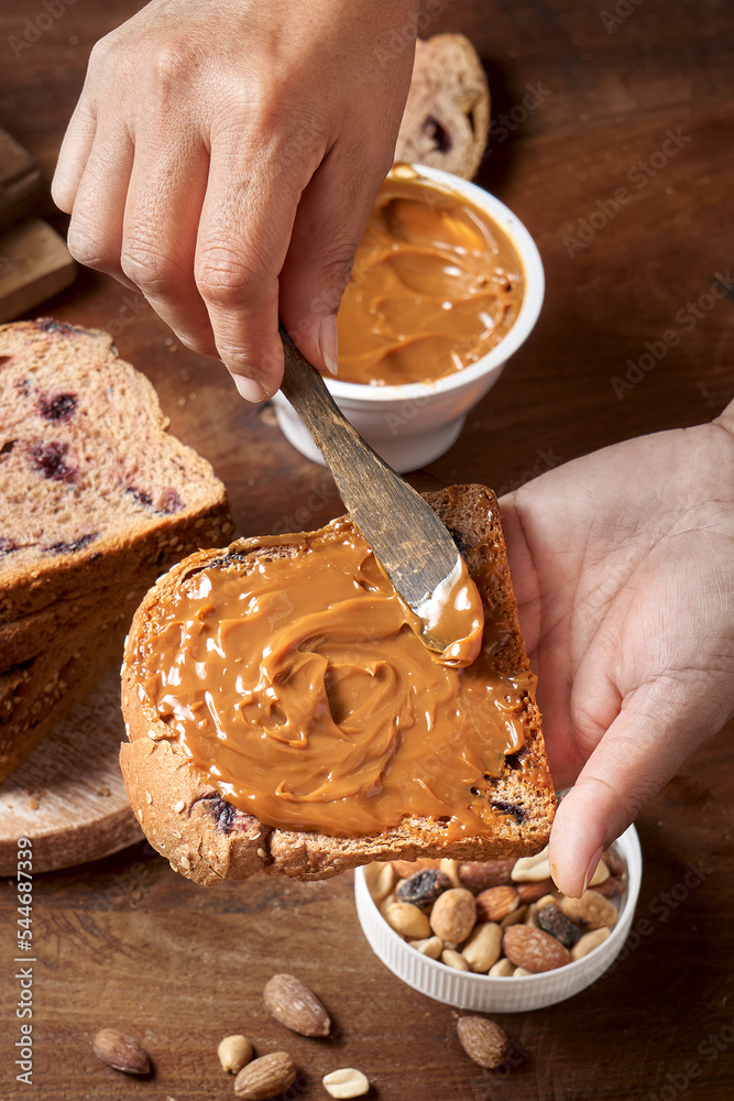 plano cerrado da manos de mujer untando manjar en pan integral con ...