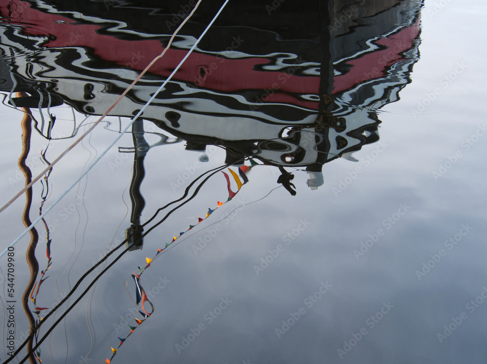 Reflexion and mirroring of black boat in blue water. Abstract distorted ...