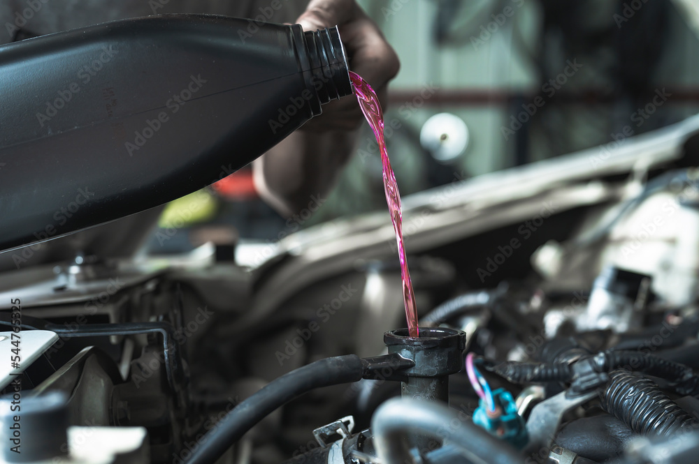 Auto mechanic filling pre-mixed long life coolant fluid in car radiator ...