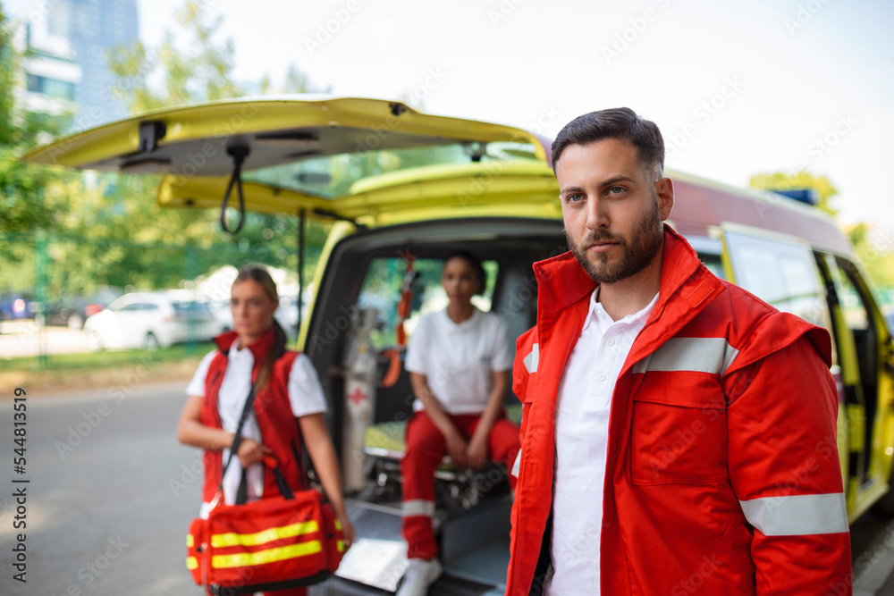 Young man, paramedic standing rear of the ambulance. paramedics by the ...