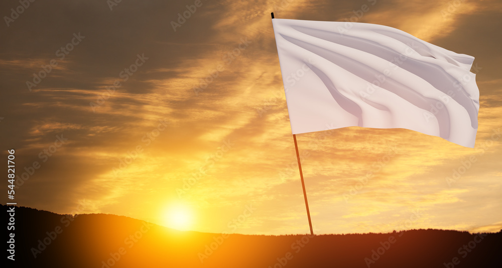 White flag waving in the wind on flagpole against the sunset sky with ...