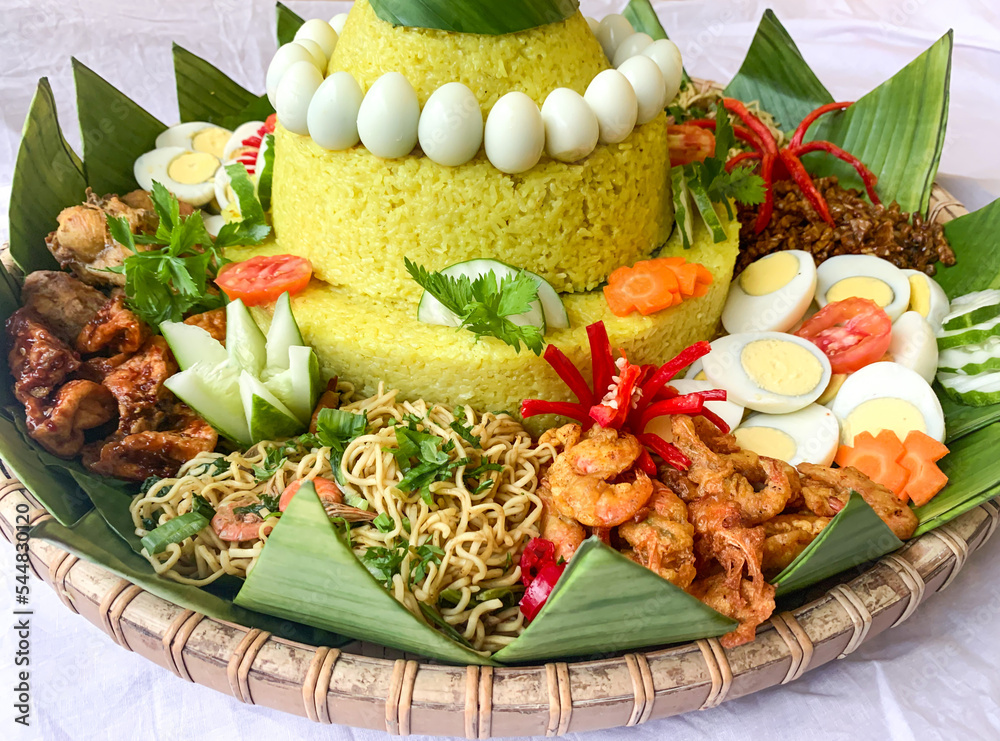 Traditional dish named Nasi Tumpeng, yellow rice cone shape with ...