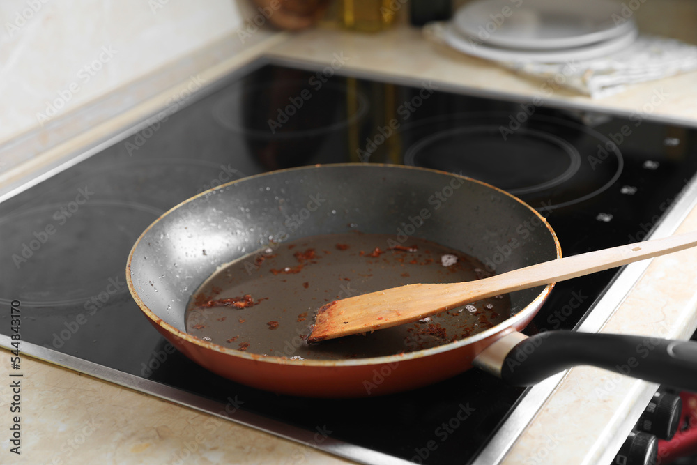 Poster Affiche Frying pan with spatula and used cooking oil on stove 40x26.7 cm