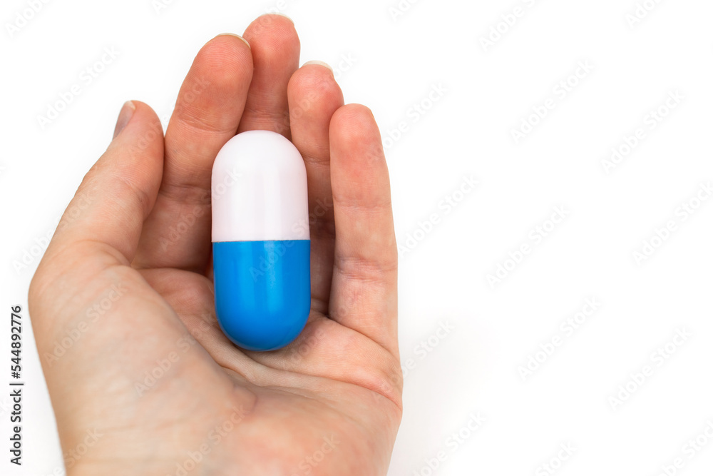 huge pill capsule in a female hand on a white background. medical drug ...