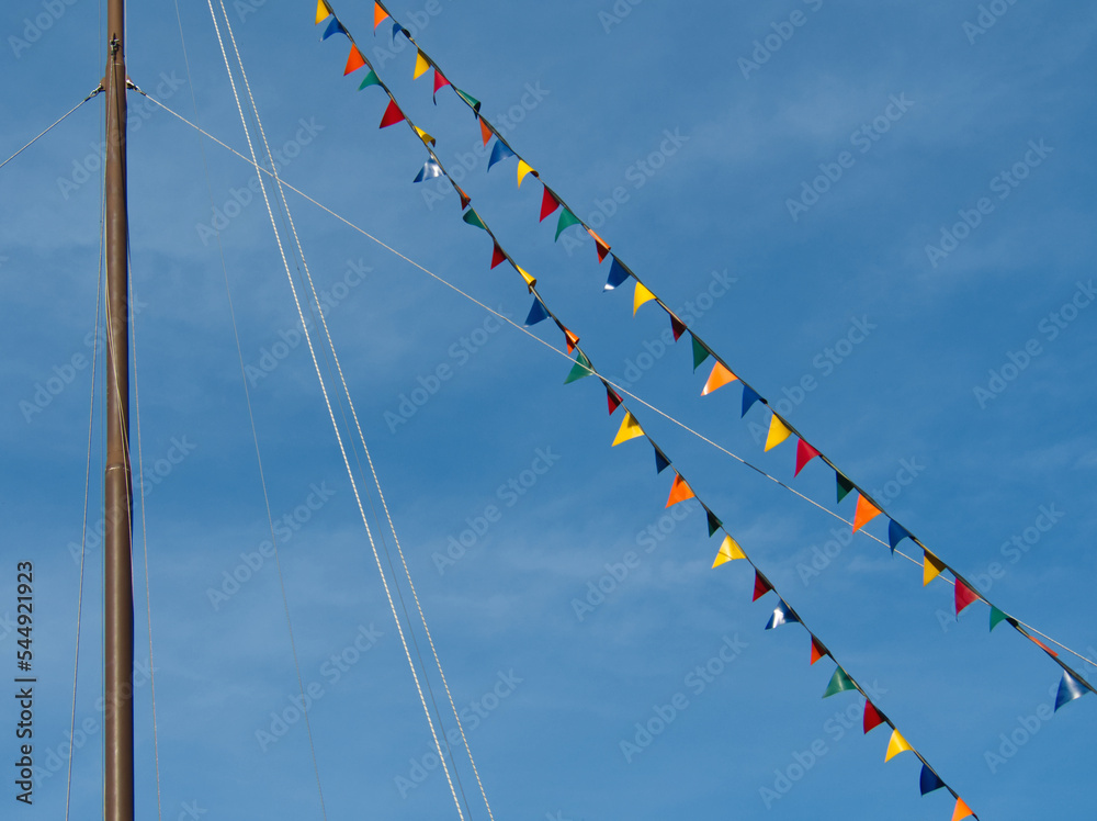Boat mast draped in colorful flags and pennants on blue sky background ...