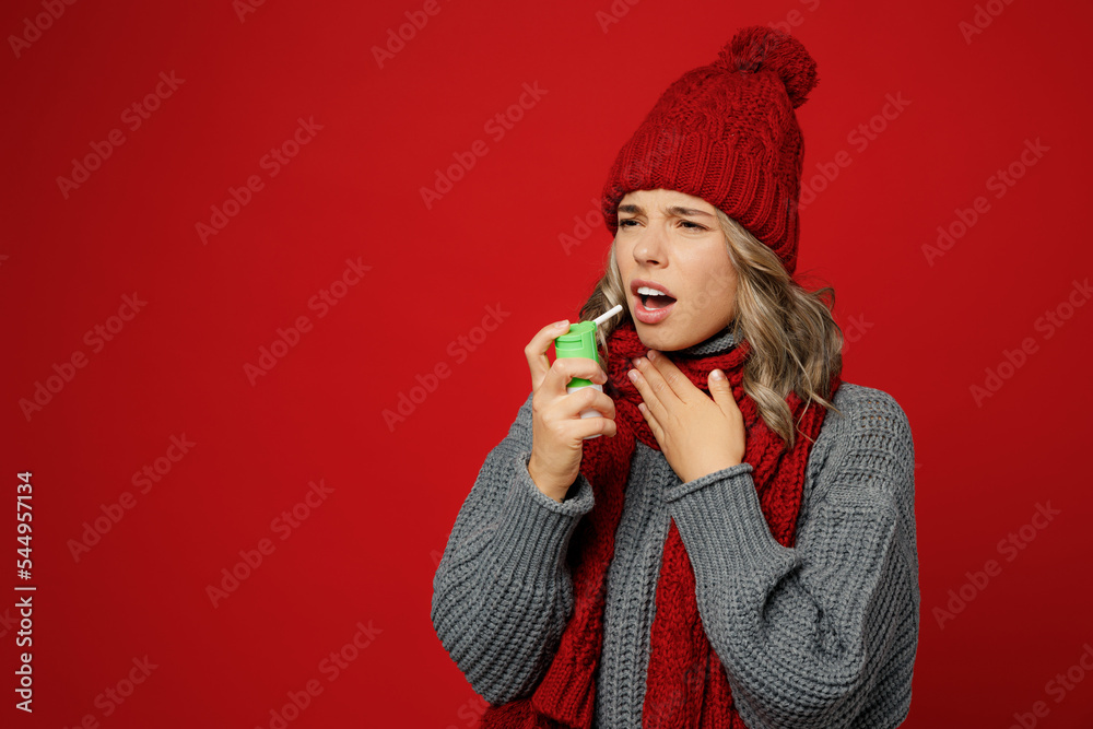Young woman in grey sweater scarf hat use spray suffer from sore throat ...