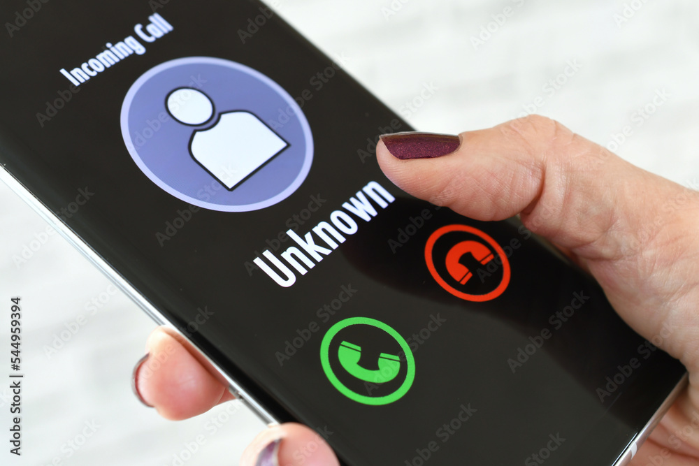 Hand holding cellphone with incoming call from Unknown Caller - fraud ...
